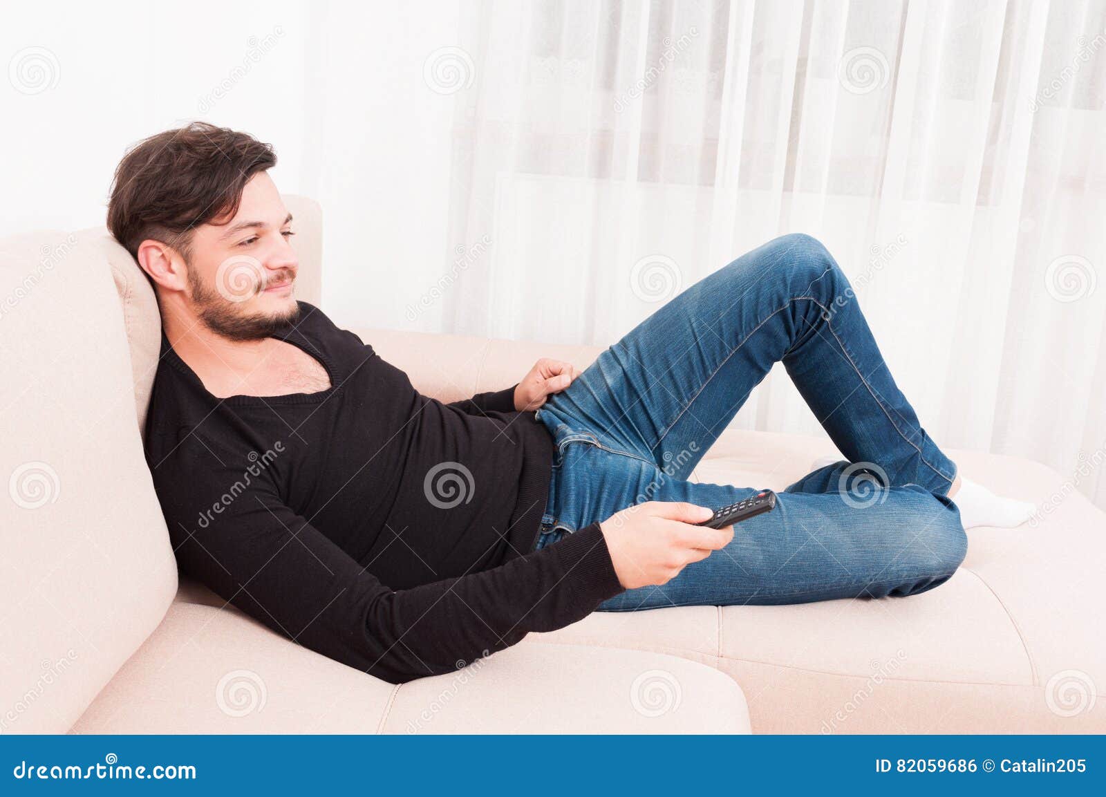 Man Laying on Sofa Holding Remote Control and Smiling Stock Photo ...