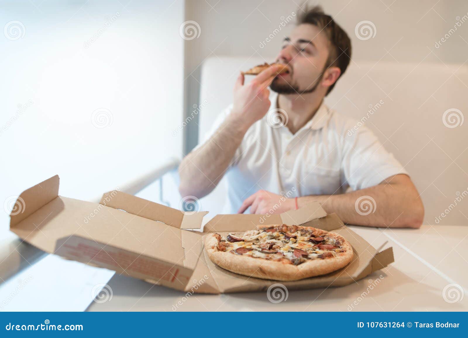 A Man in Light Clothing Eats a Delicious Pizza from a Cardboard Box ...