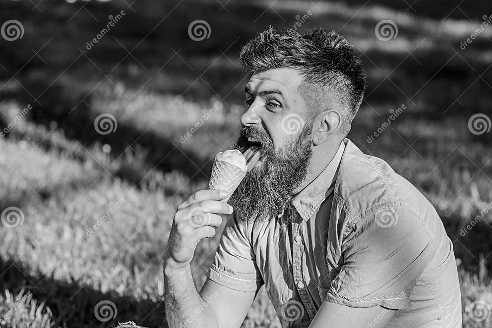 Man With Long Beard Eats Ice Cream While Sits On Grass Bearded Man
