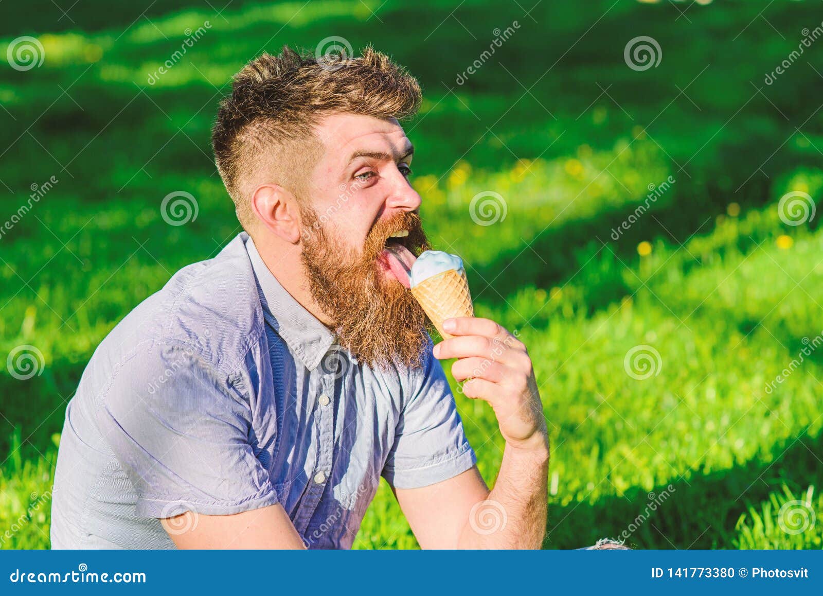 Man With Long Beard Eats Ice Cream While Sits On Grass Bearded Man