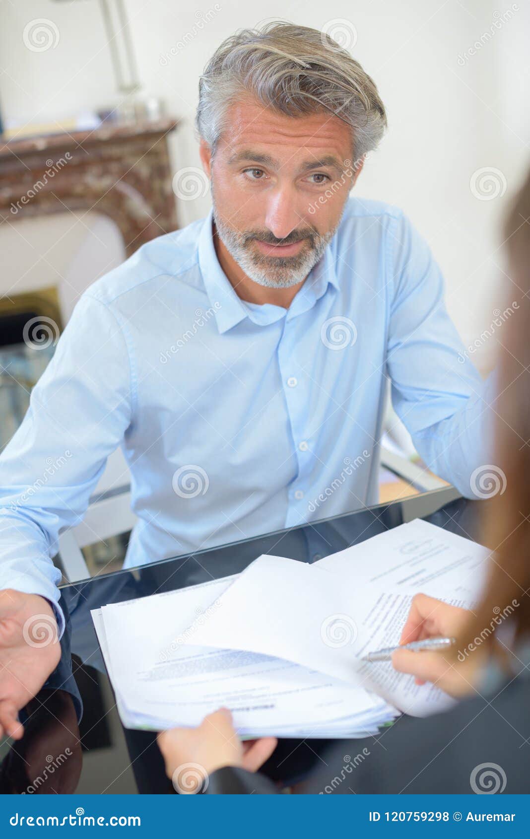 Man Looking Doubtfully at Lady Passing Him Paperwork Stock Photo ...