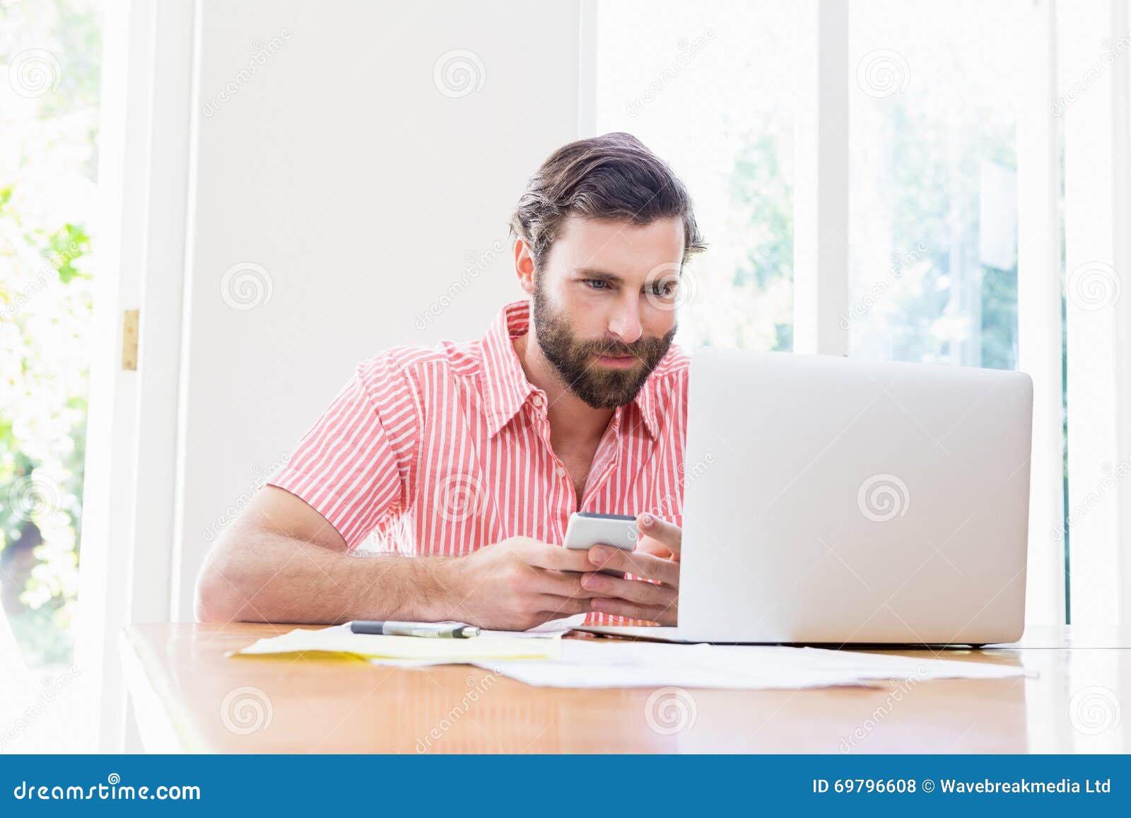 Man Looking at Laptop while Using Mobile Phone Stock Photo - Image of ...