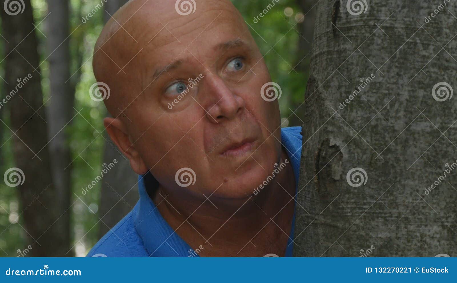 Man Looking Scared with Terrified Eyes is Hiding after a Tree in the ...
