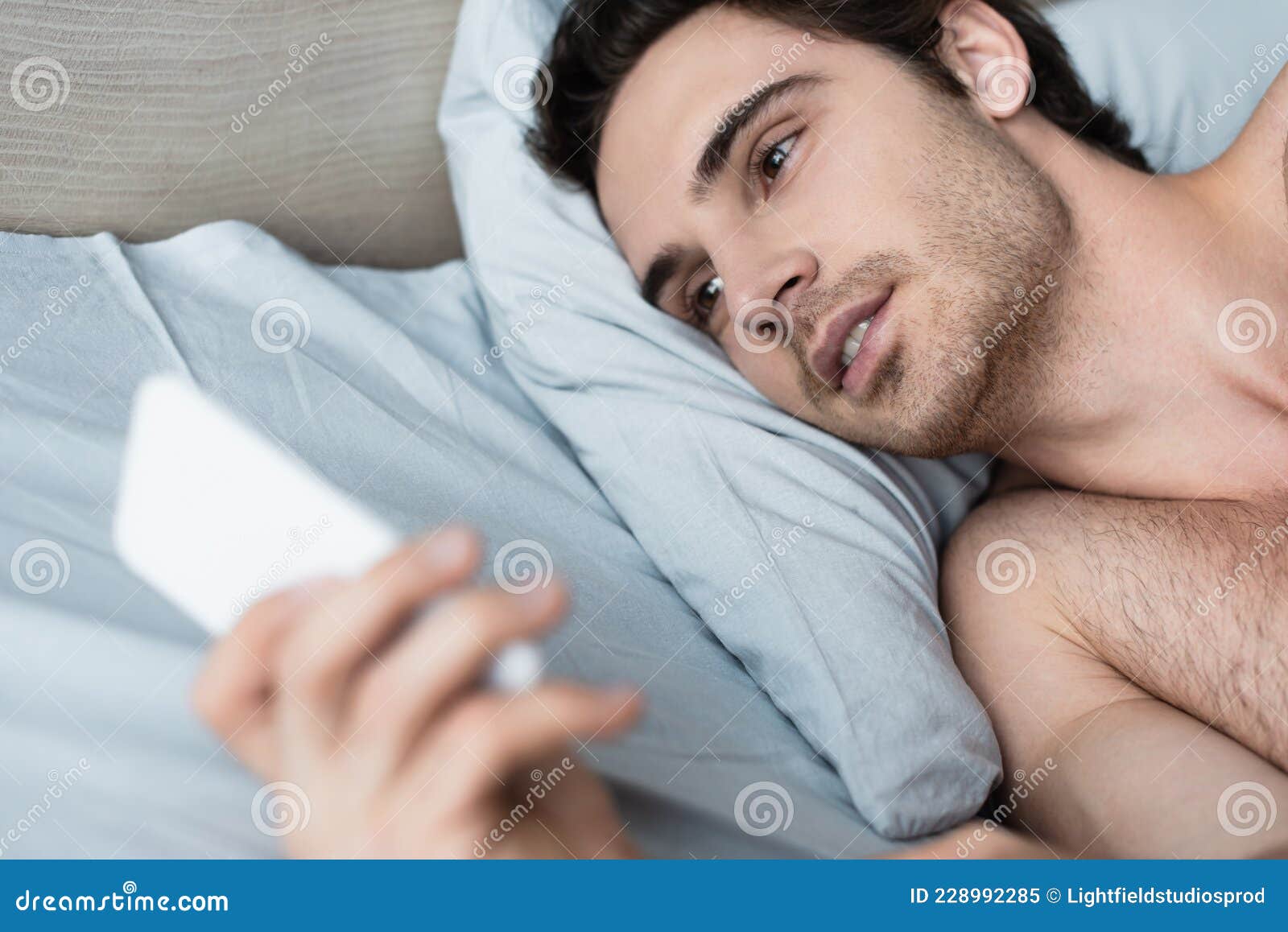 Man lying in bed and using stock image. Image of adult - 228992285