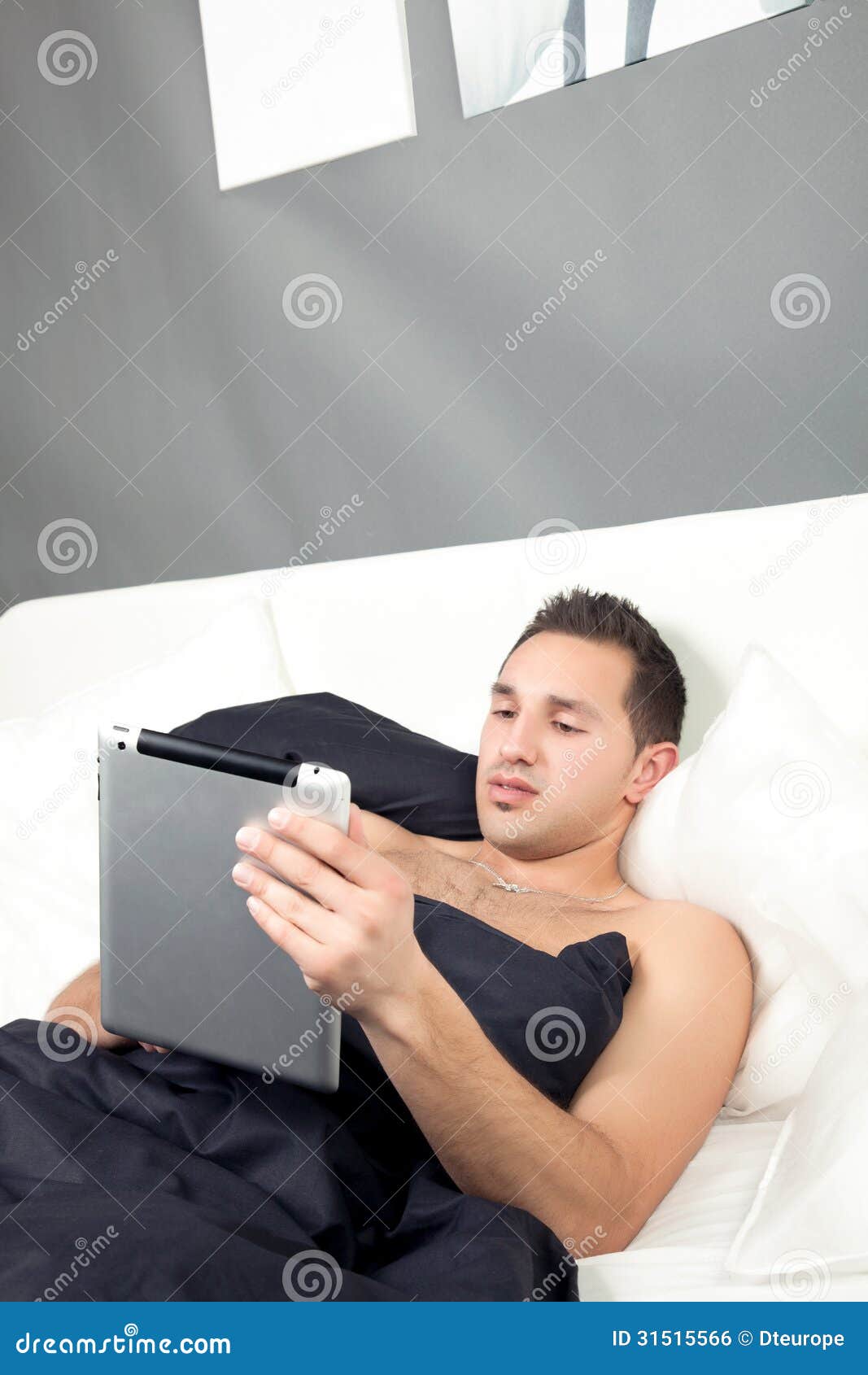 Man Lying in Bed Working on His Tablet Stock Photo - Image of duvet ...
