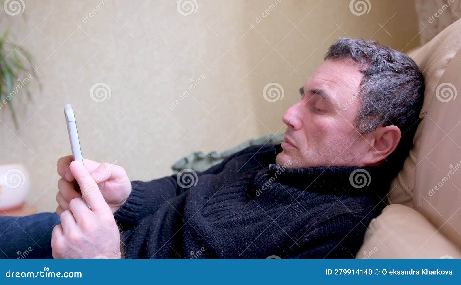 Man Lying Down on Couch while Looking at His Cell Phone Alone at Night ...