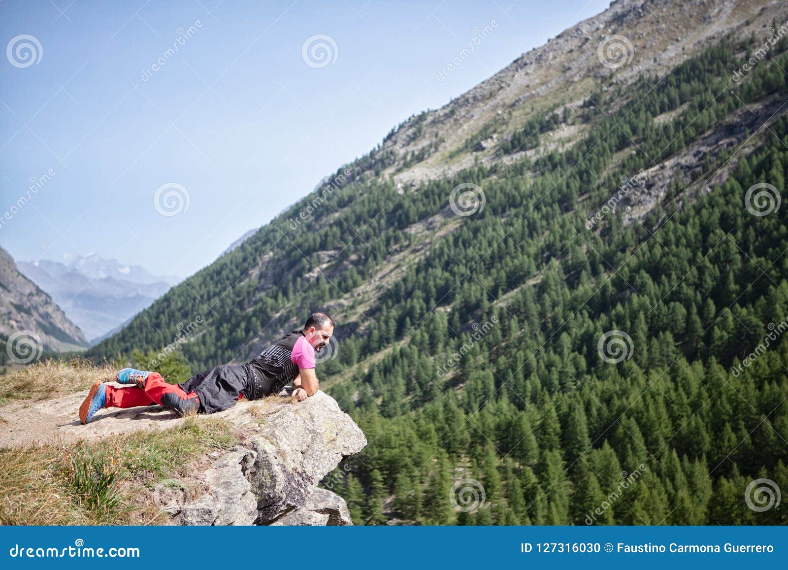 Man Lying on Precipice Looking at Mountainous Landscape Stock Photo ...