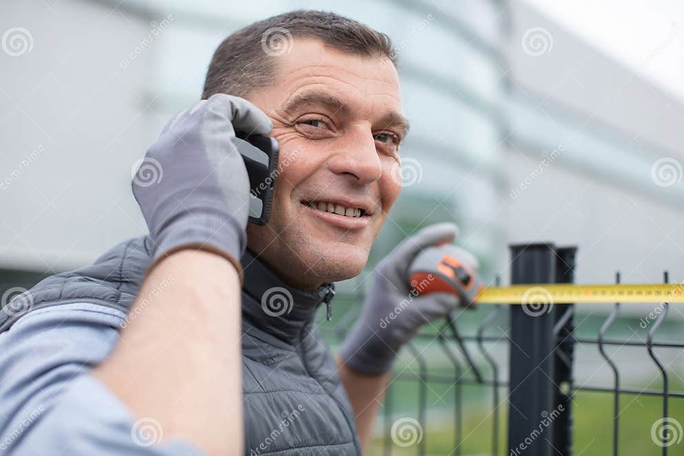 Man Measures Fence and Talks on Smartphone Stock Image - Image of caucasian, workman: 321921411