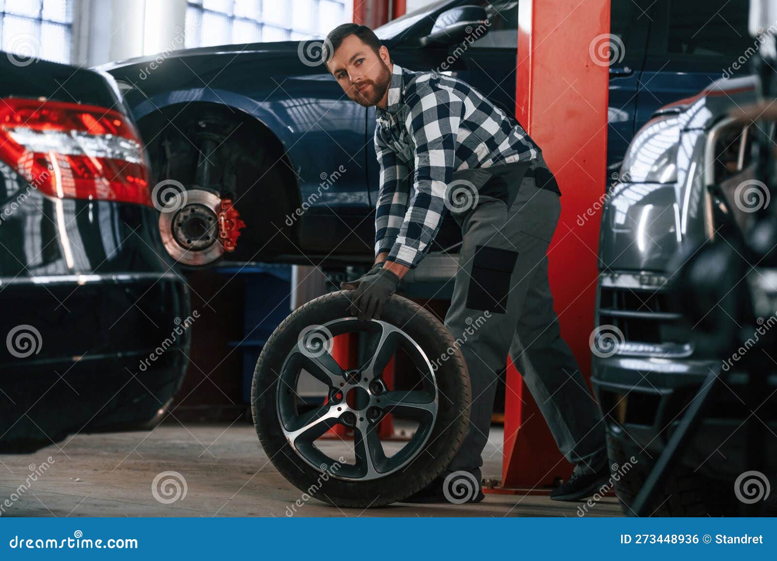 Man is Moving the Wheel. Employee is Working in the Auto Salon Stock ...
