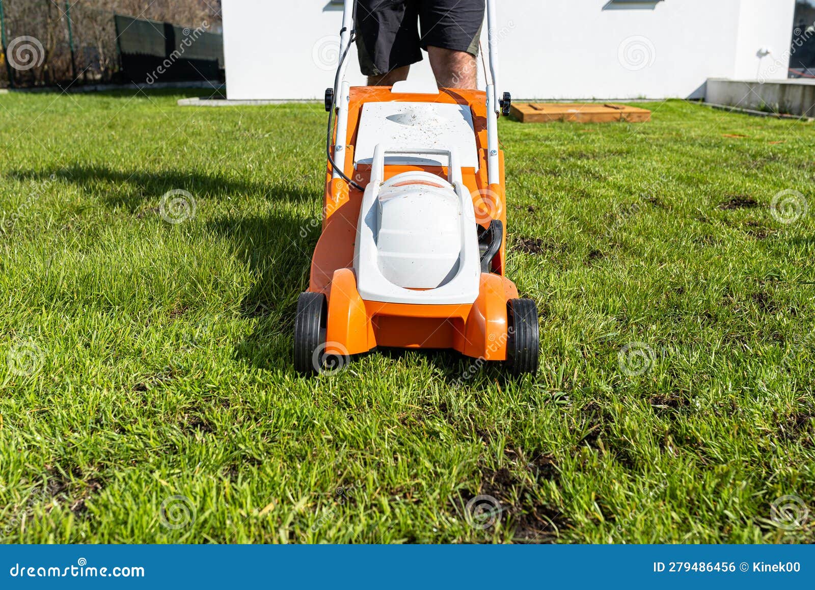 A Man Mows the Grass with an Orange Electric Mower, Stock Photo - Image ...
