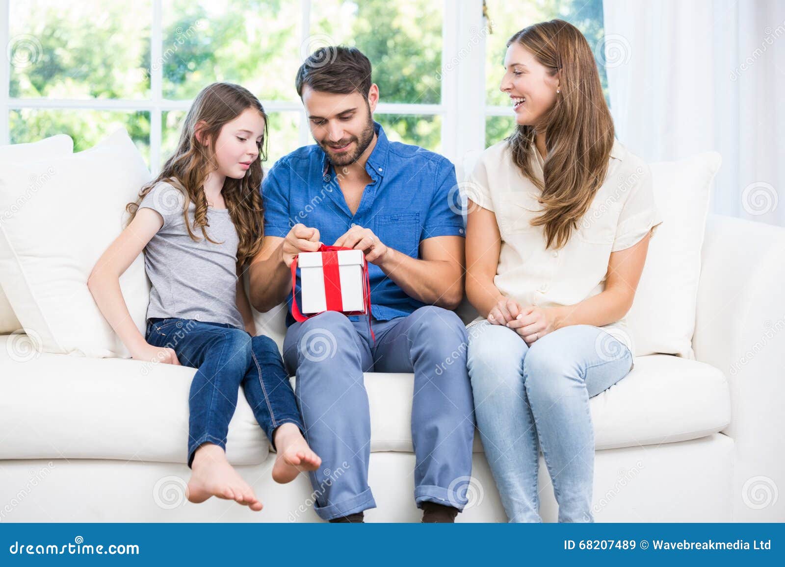 Man Opening Gift while Sitting on Sofa with Family Stock Image - Image ...