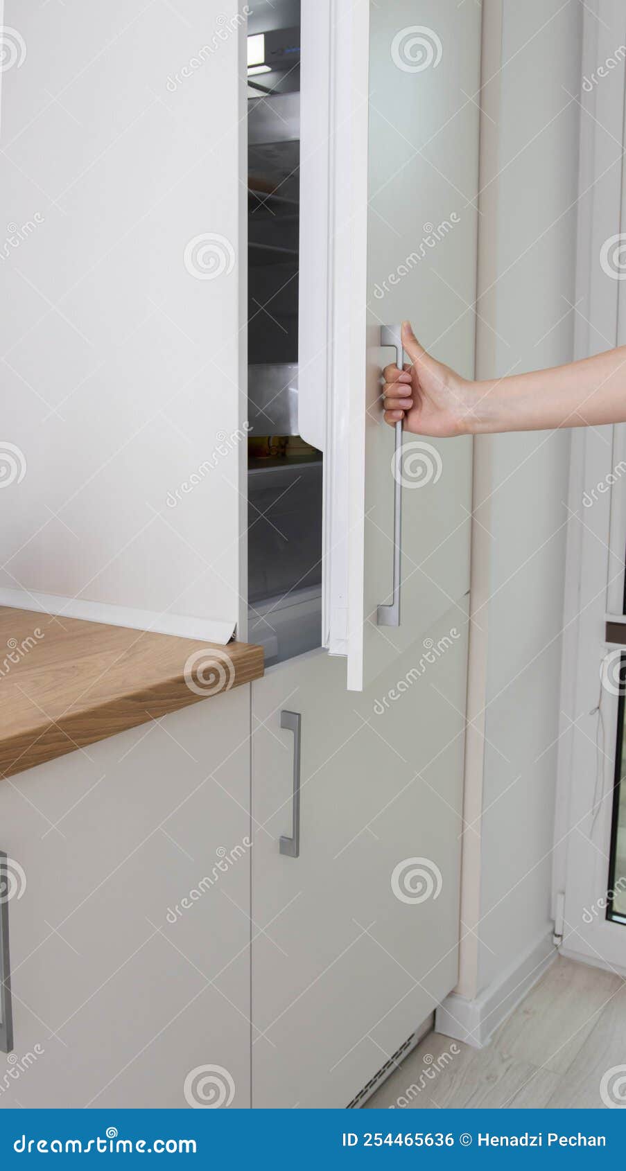 A Man Opens the Door of a Built-in Refrigerator in the Kitchen. Modern ...