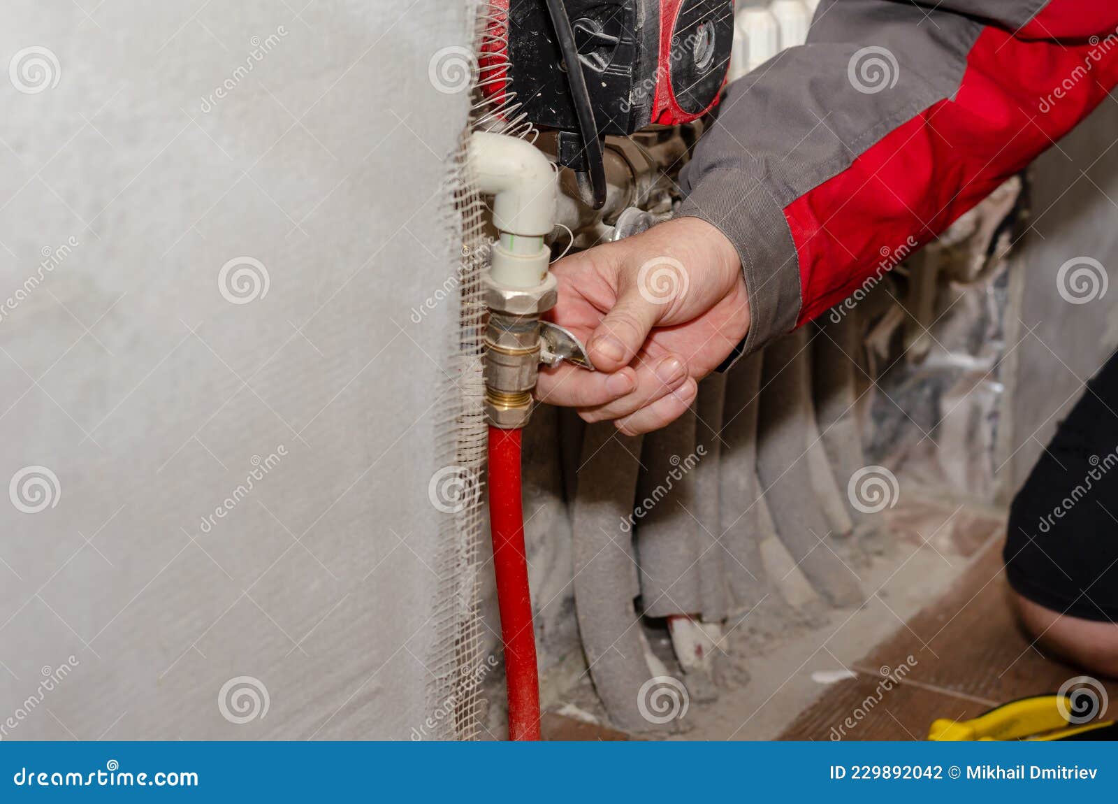 A Man Opens a Gate Valve on the Piping of a Space Heating System Stock ...