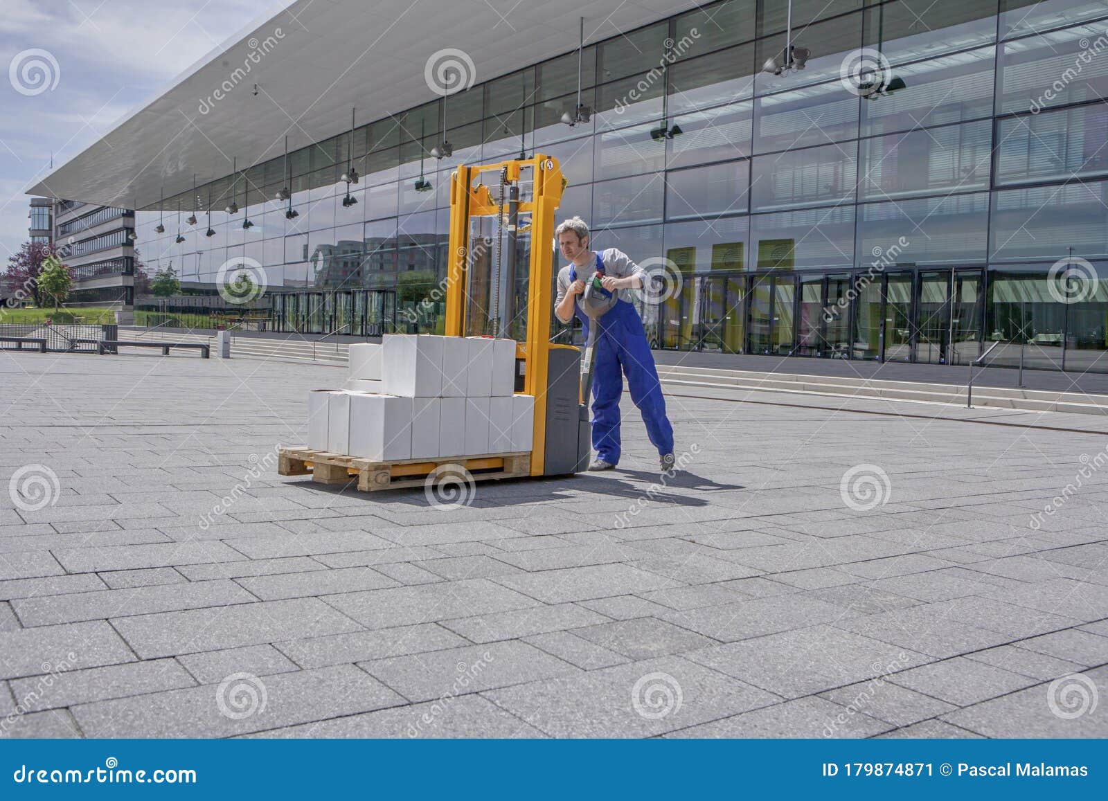 Man in Overall Operates an Electric Stacker Loaded with Boxes Stock ...