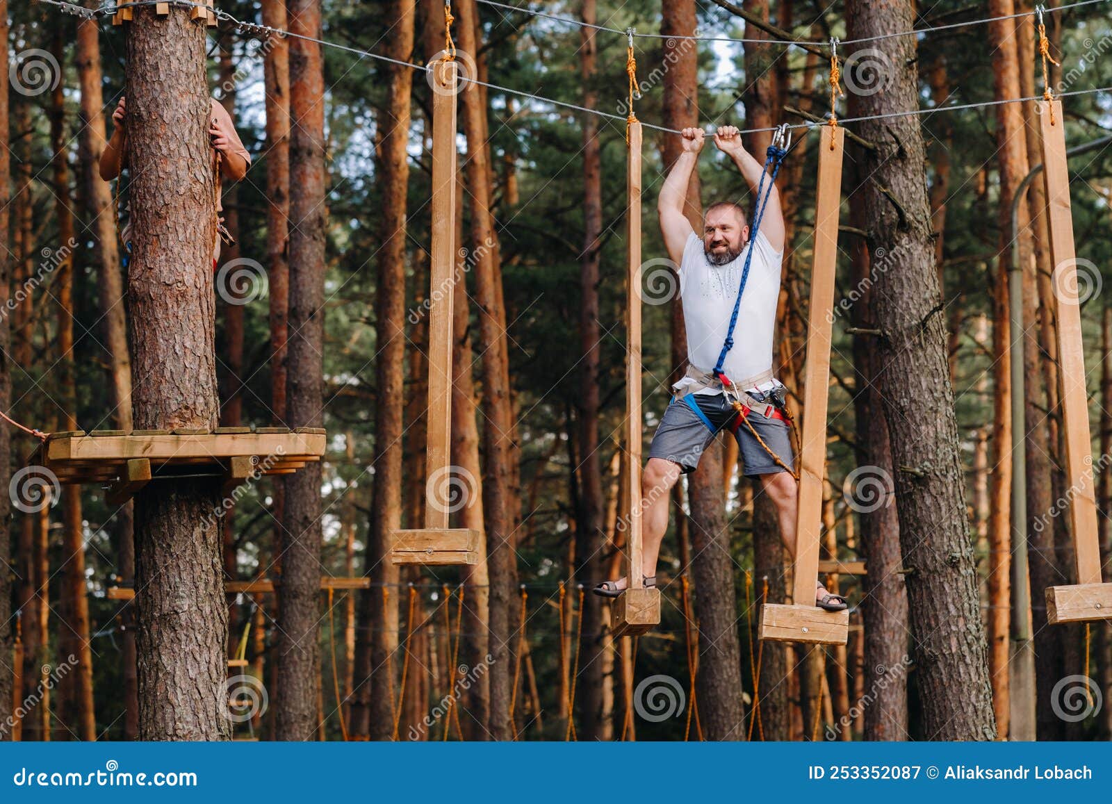 A Man Overcomes an Obstacle in a Rope Town. a Man in a Forest Rope Park ...