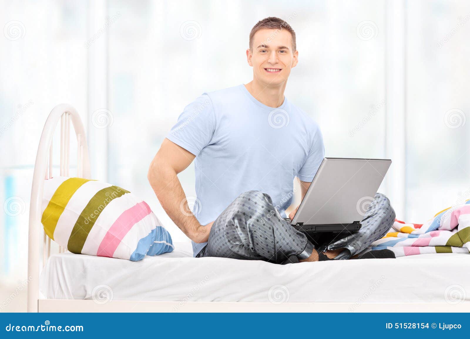 Man in Pajamas Working on a Laptop Seated on a Bed Stock Photo - Image ...