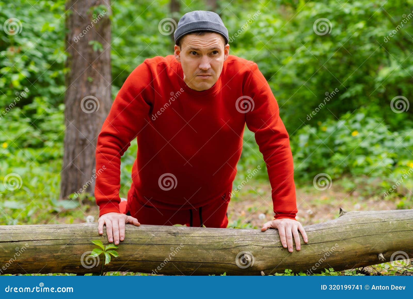 A Man Performs Push-ups Using the Log As Support. the Backdrop is a ...