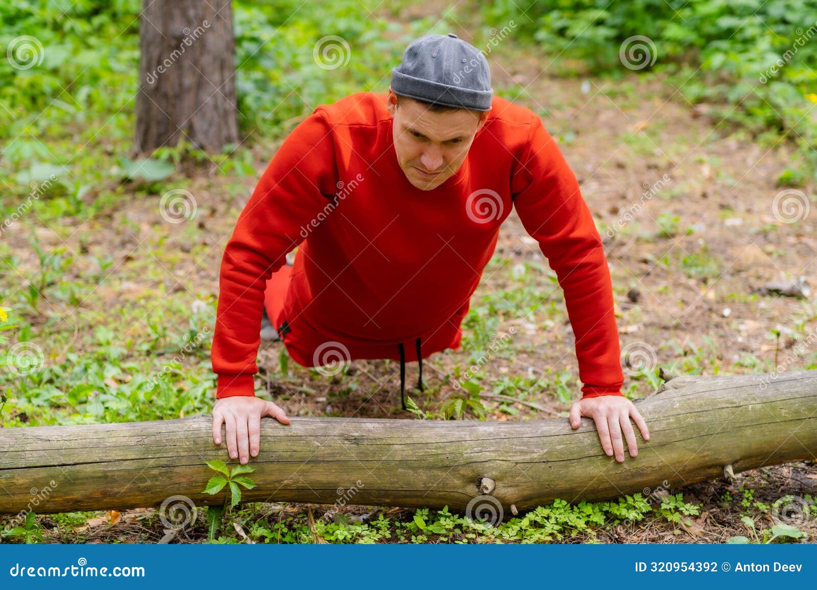 A Man Performs Push-ups Using the Log As Support. the Backdrop is a ...