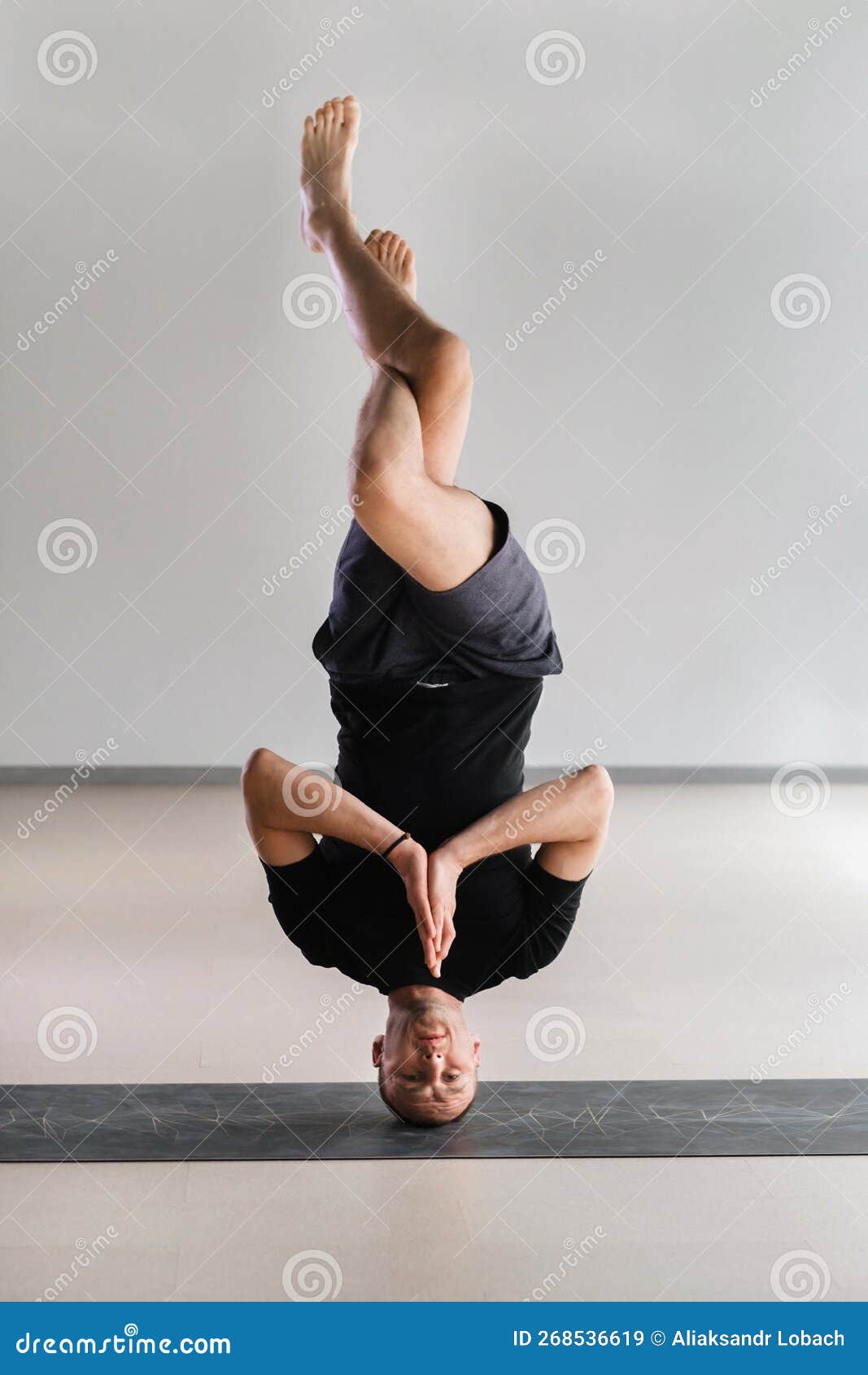 A Man Performs a Yoga Pose with Support on His Head in the Gym. Yogi in ...