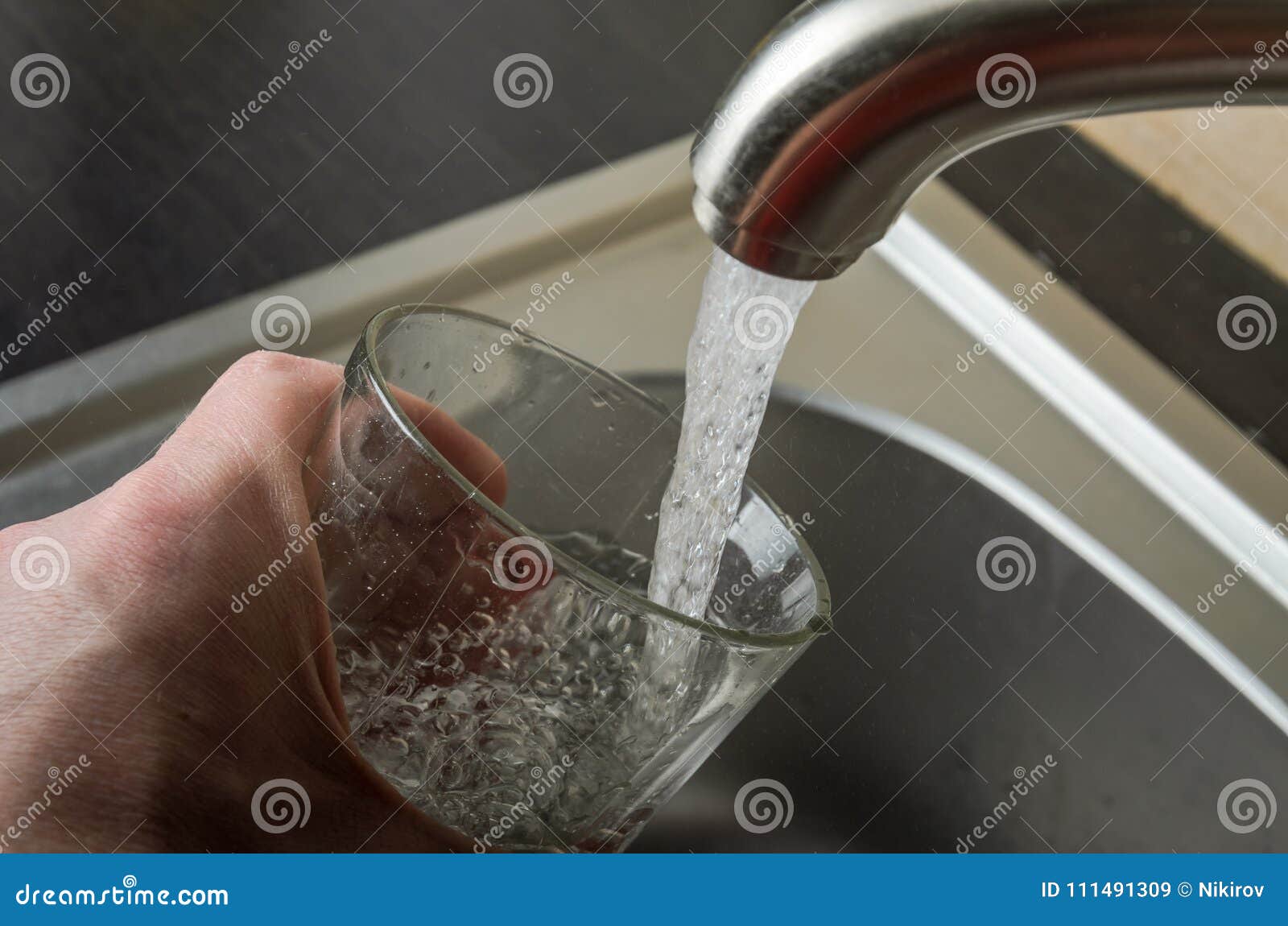 A Man Picks Up Drinking Water in a Glass from Under the Kitchen Faucet ...