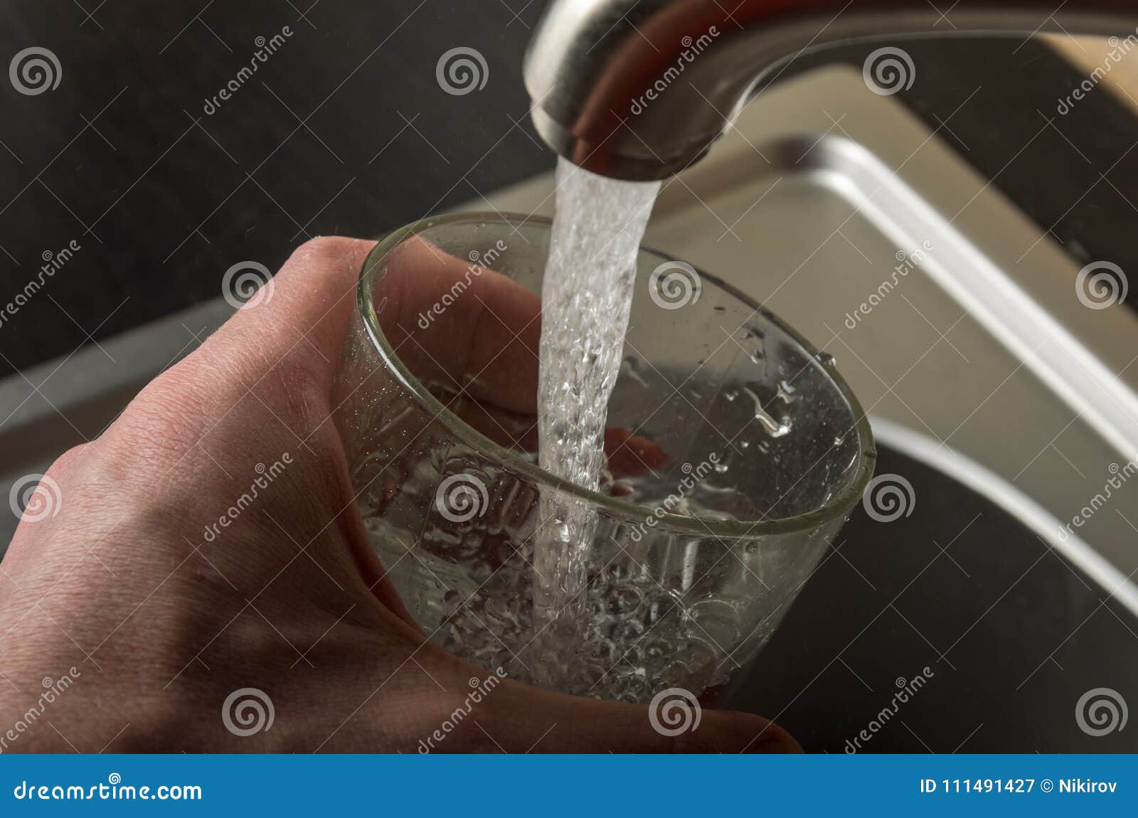 A Man Picks Up Drinking Water in a Glass from Under the Kitchen Faucet ...