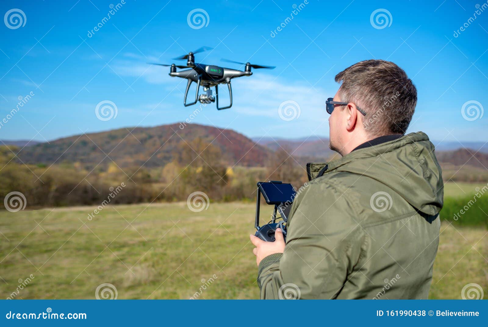 Man Pilots a Drone in Nature by Controlling it from a Remote Control ...