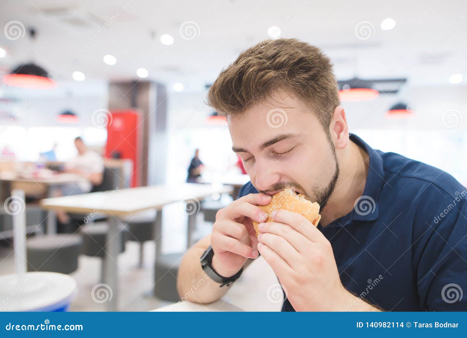 Man with Pleasure Bites an Appetizing Burger on the Background of a ...