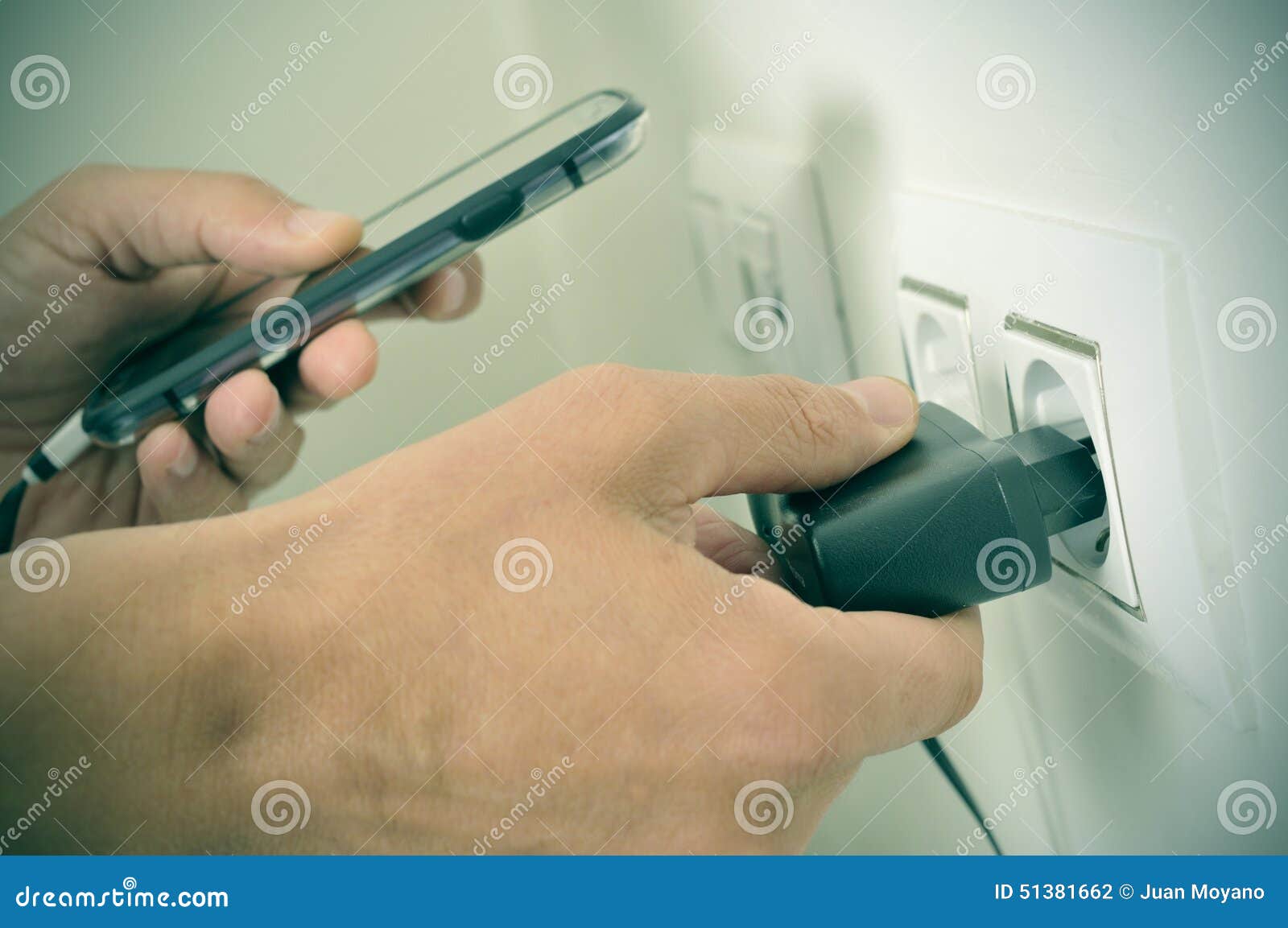 Man Plugging in the Plug of His Smpartphone in a Socket, with a Stock ...