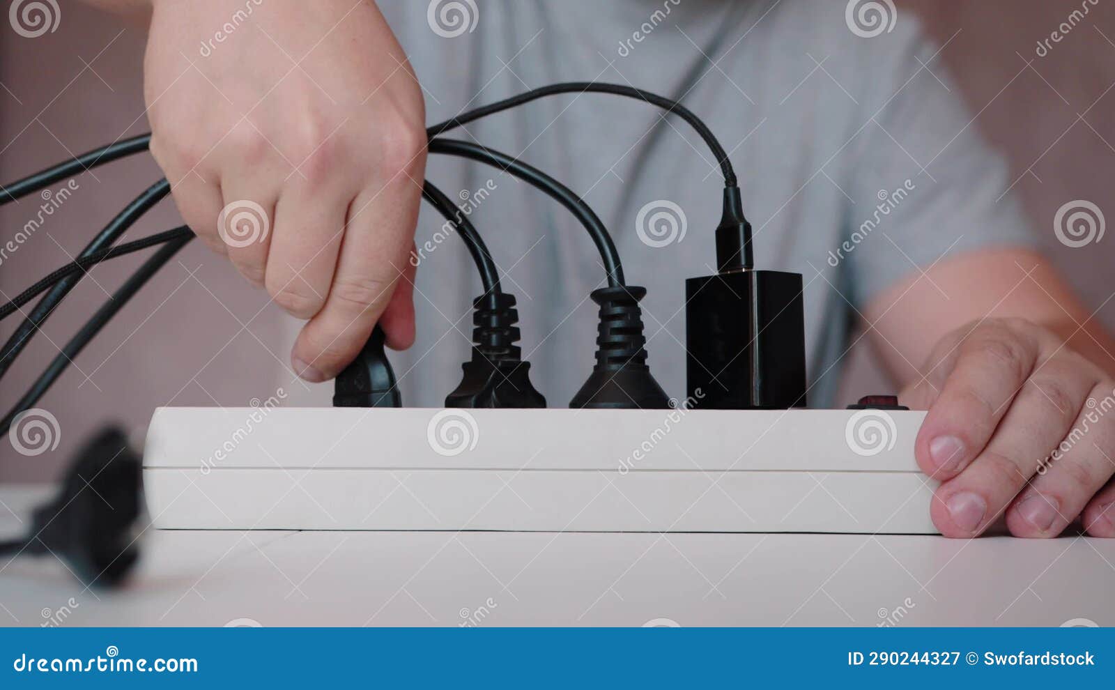 A Man Plugs Many Electrical Plugs with Wires into One Surge Protector ...