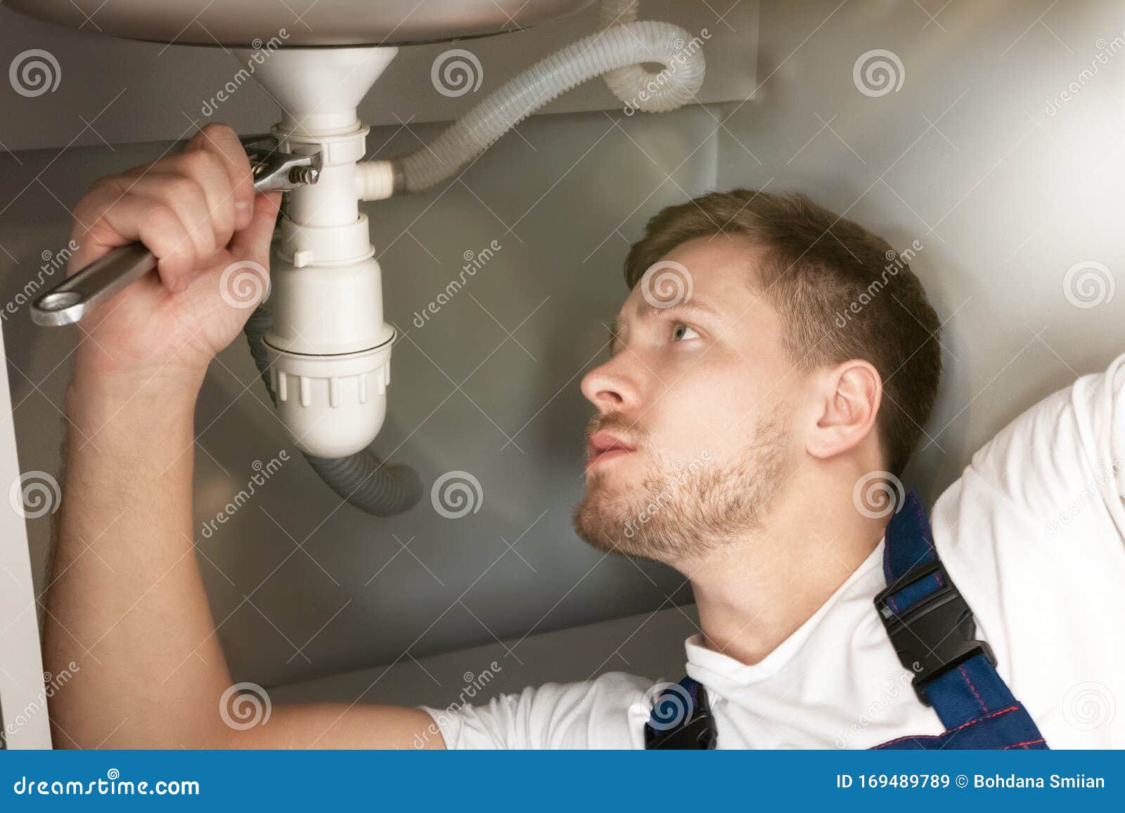 Man Plumber in Uniform Fixing the Sink Pipe with Adjustable Spanner in ...