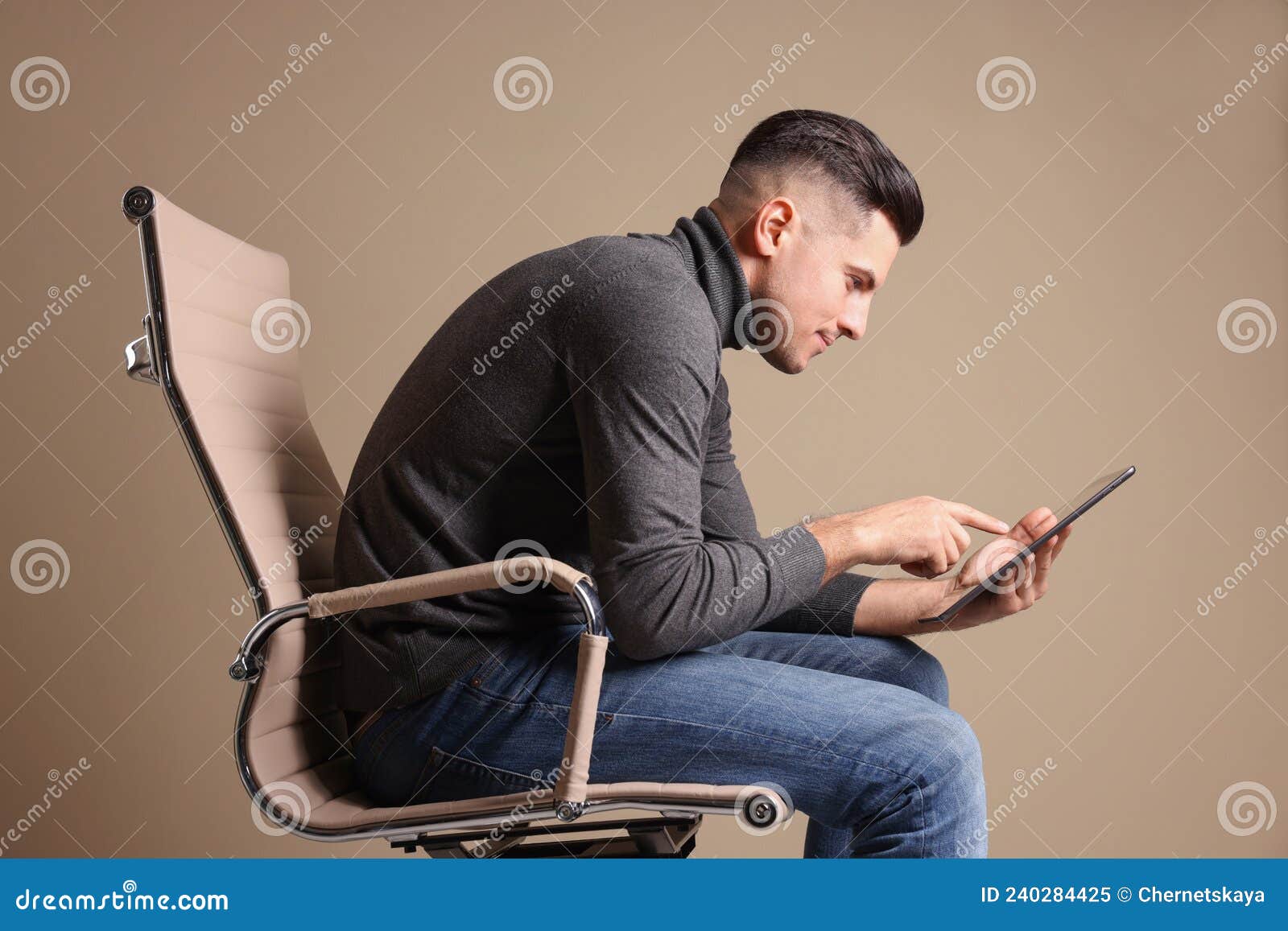 Man with Poor Posture Using Tablet while Sitting on Chair Against Beige ...