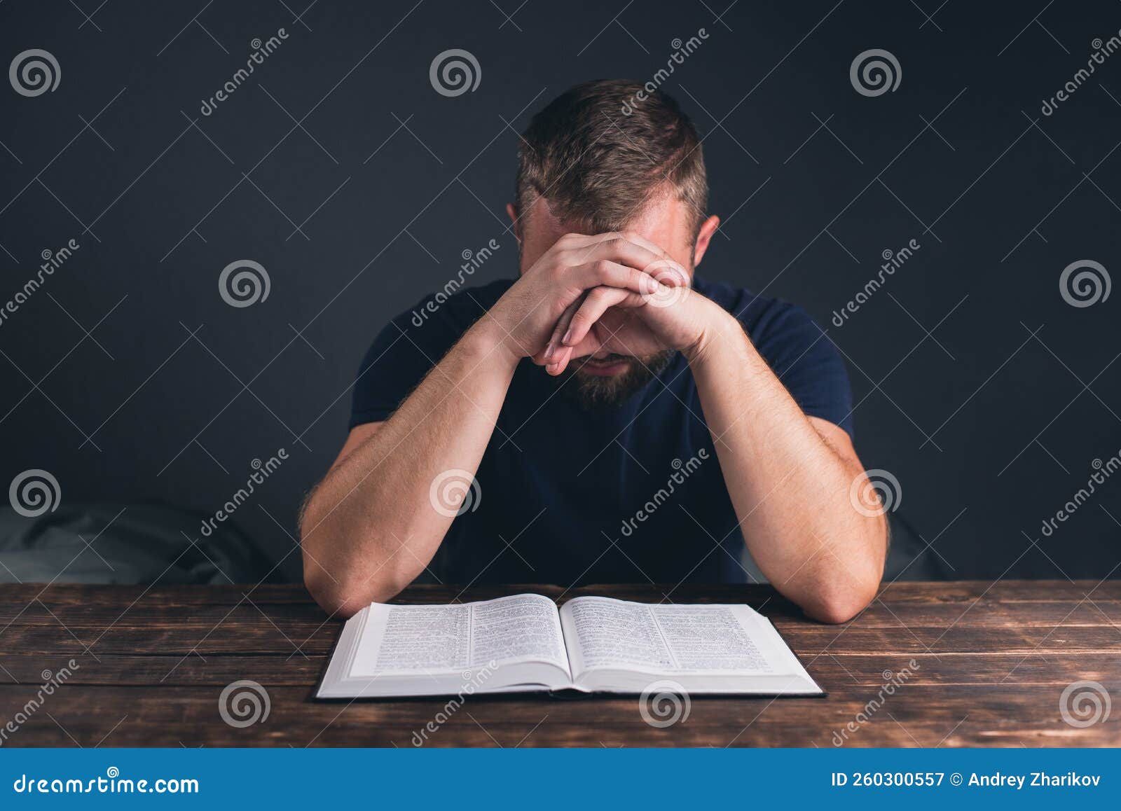 A Man Prays with Folded Hands. an Open Holy Bible on the Table. a Young ...