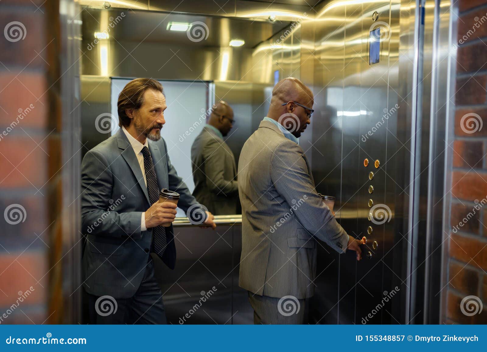 Man Pressing Button in Elevator while Standing Near Colleague Stock ...