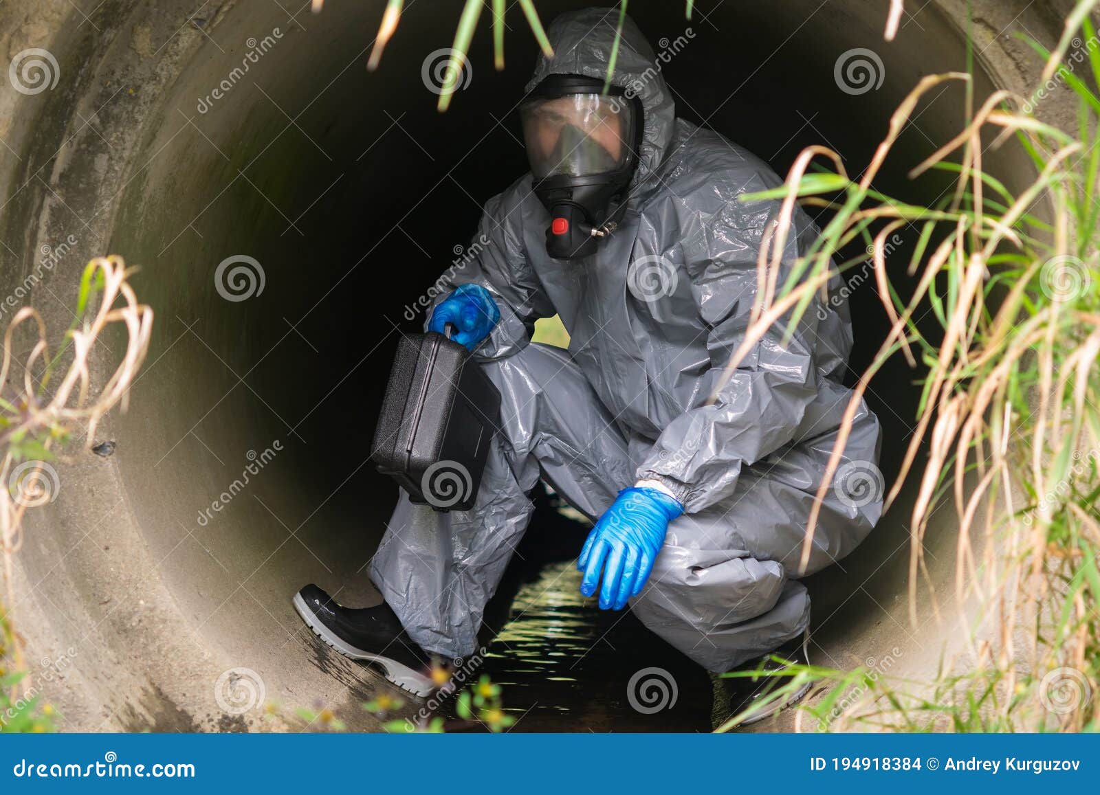 A Man in a Protective Suit and Mask Crawls Out of the Sewer after ...