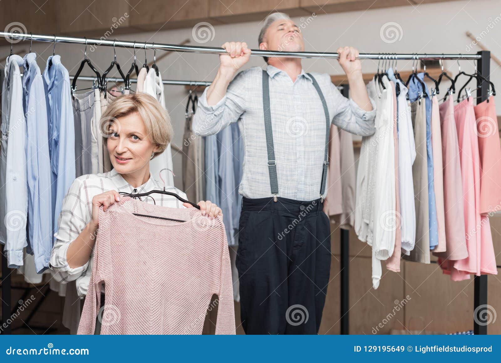 Woman Posing with Shirt while Man Pulling Up on a Clothes Rack Stock ...