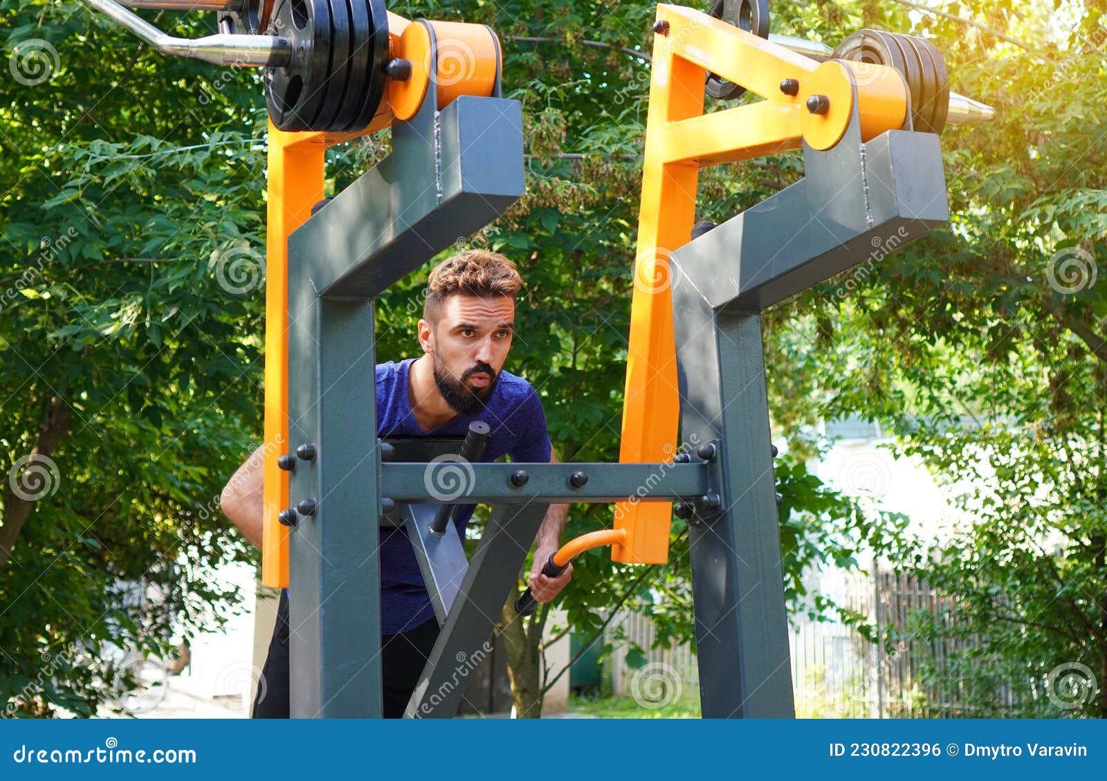 A Man Pumps His Back Muscles on a Training Equipment in the Park Stock ...