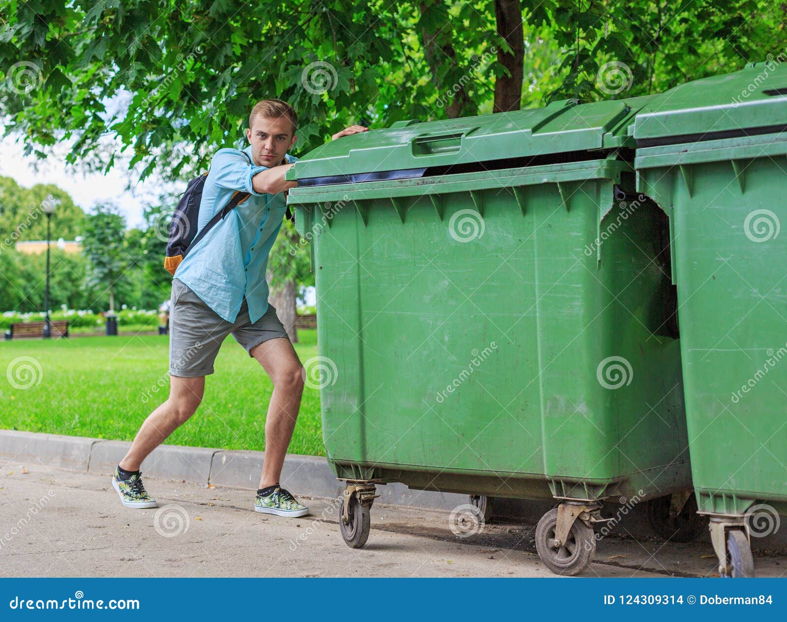 Man Pushing a Green Garbage Cans in the Park Stock Photo - Image of ...