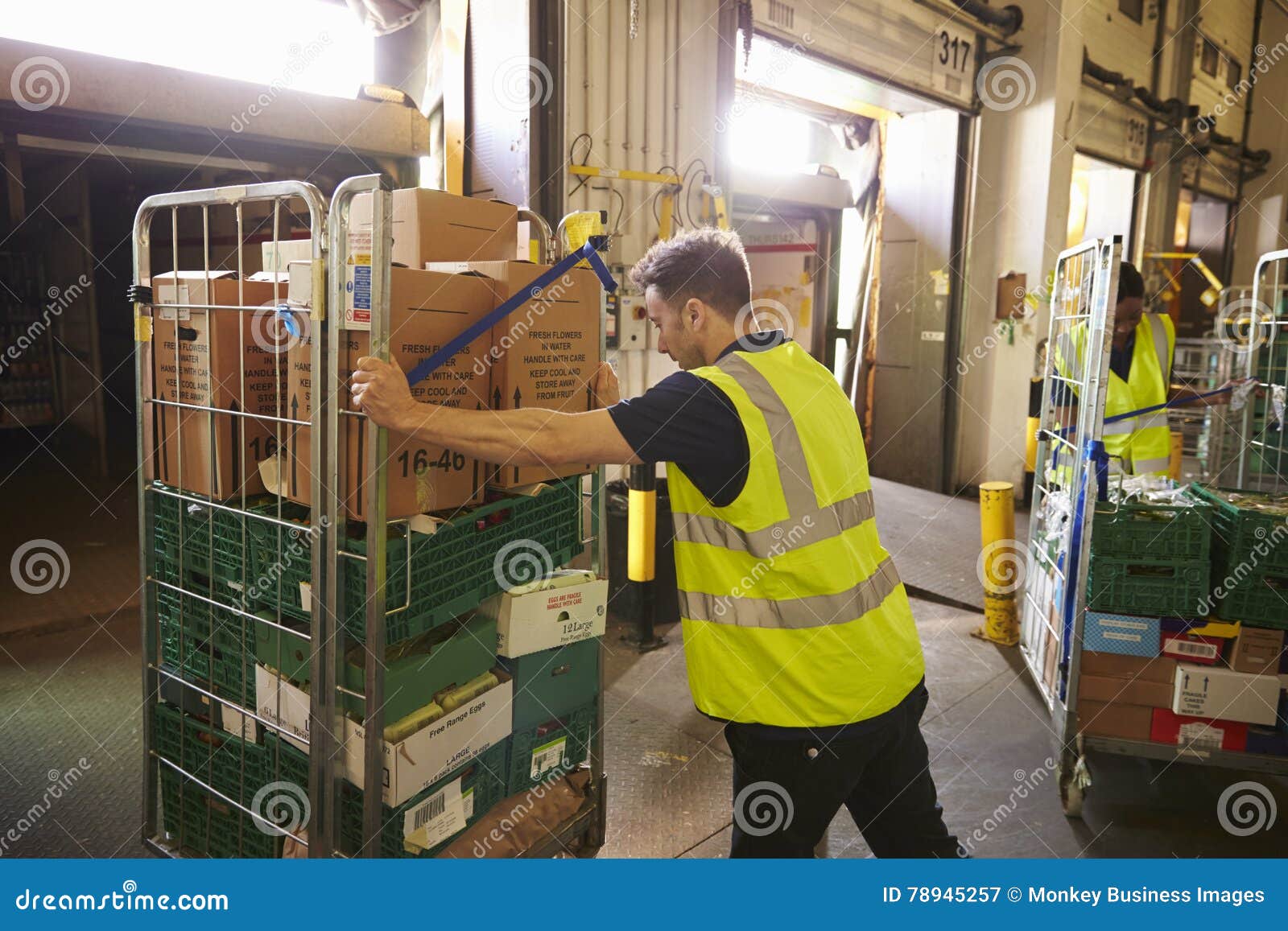 Man Pushing a Roll Cage Ready for Delivery in a Warehouse Stock Image ...