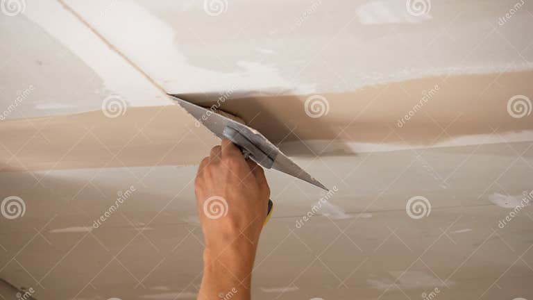 A Man Puts Putty on a Plasterboard Ceiling. Putty for the Joints of ...
