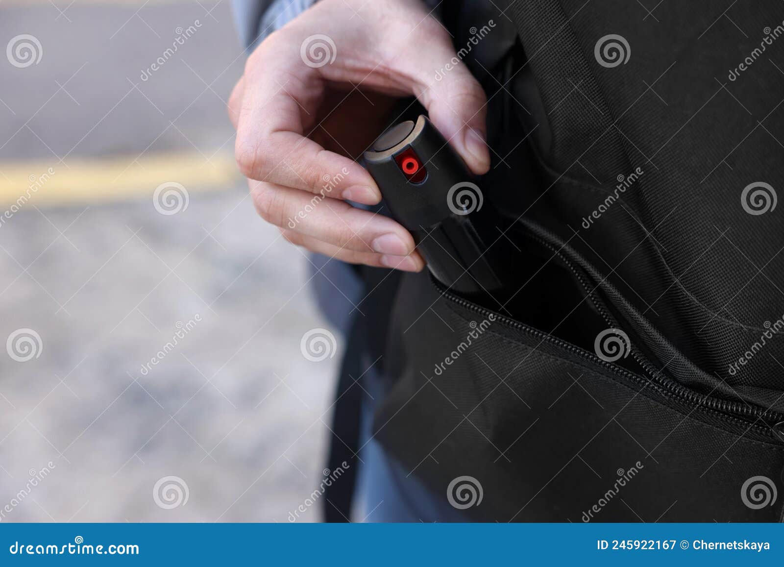 Man Putting Pepper Spray into Backpack Outdoors, Closeup. Space for ...