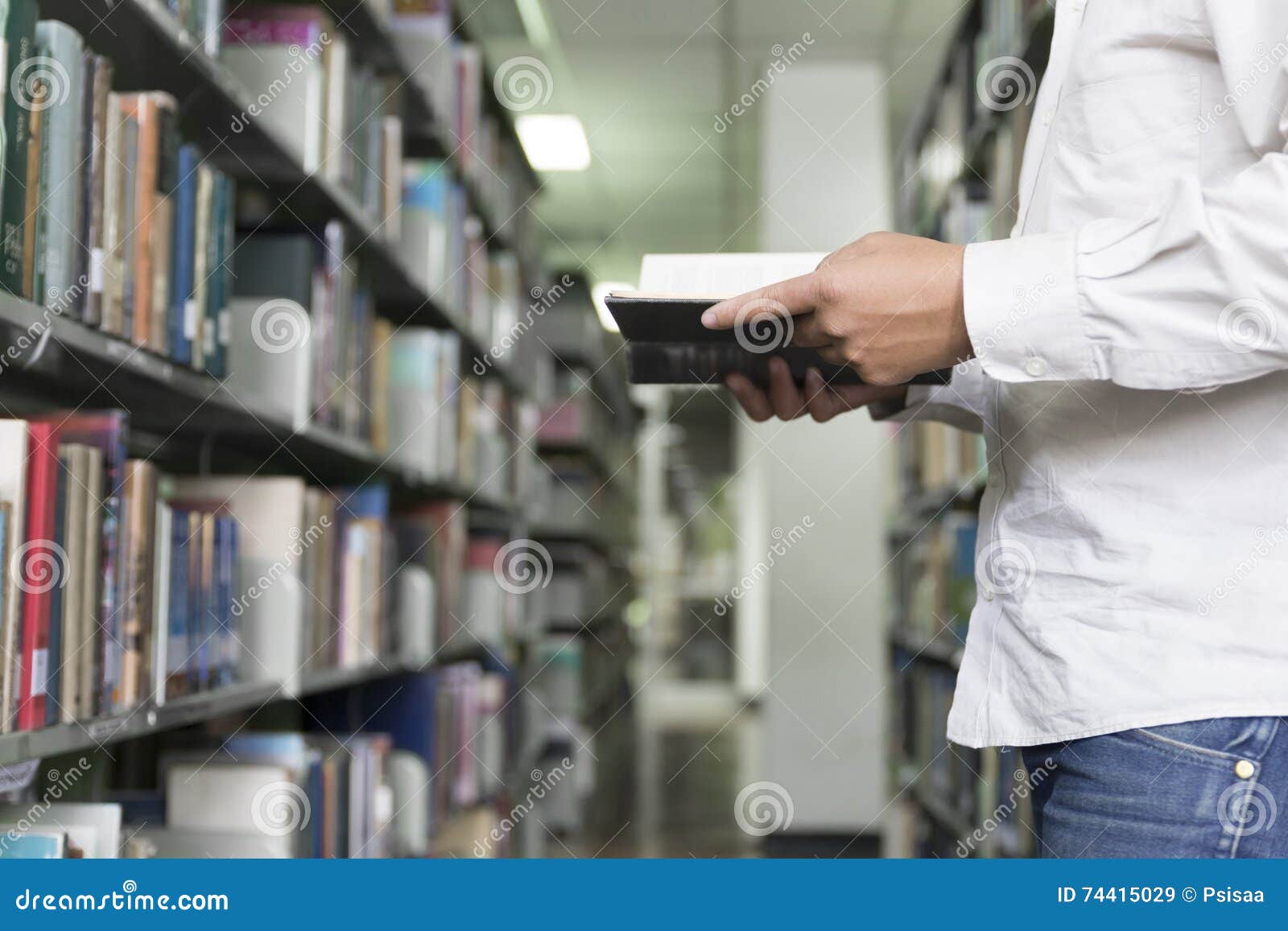 Man Reading Book in Aisle in Library Stock Image - Image of casual ...