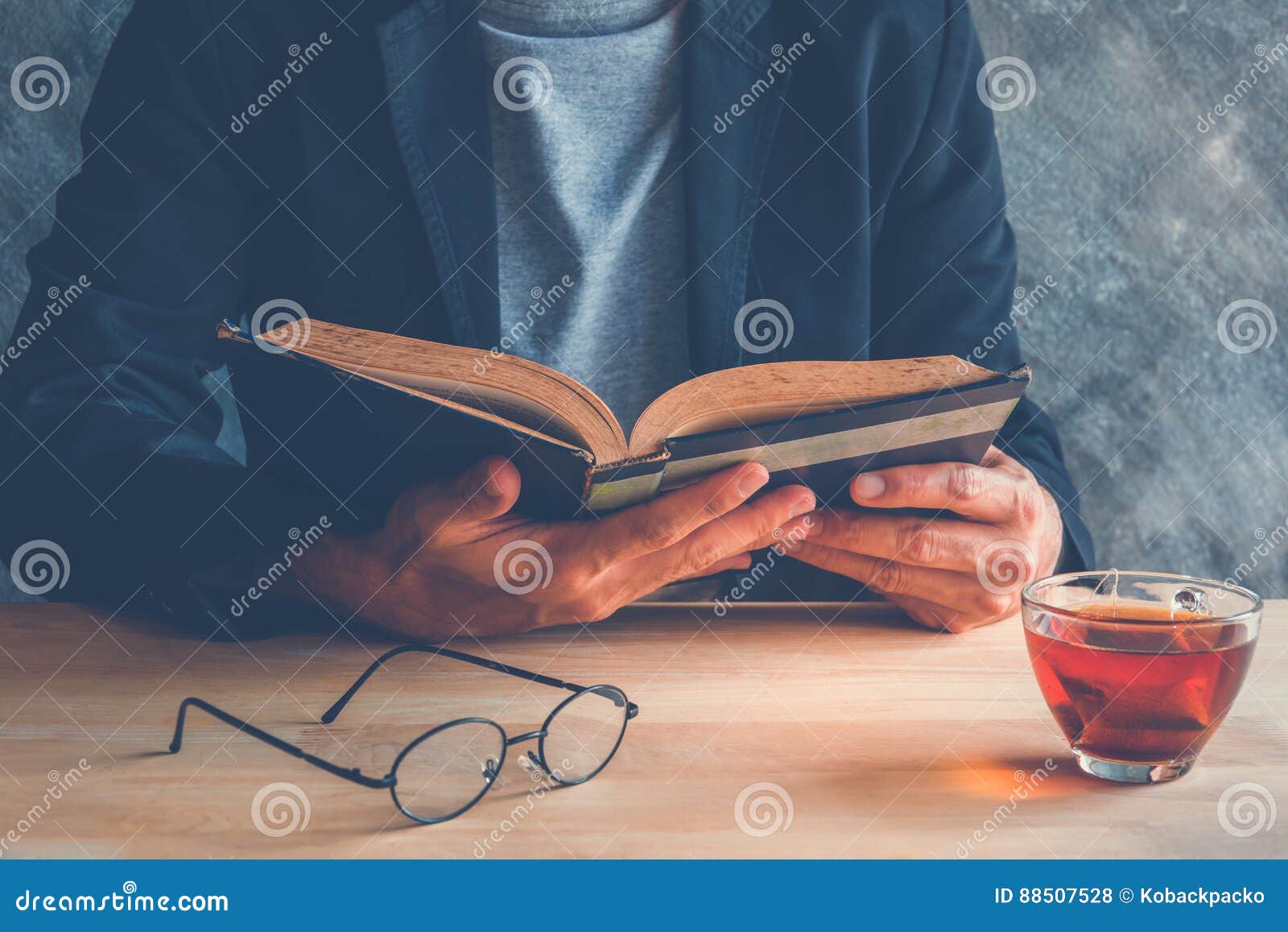 A Man Reading a Book with a Cup of Tea on Table Stock Photo - Image of ...
