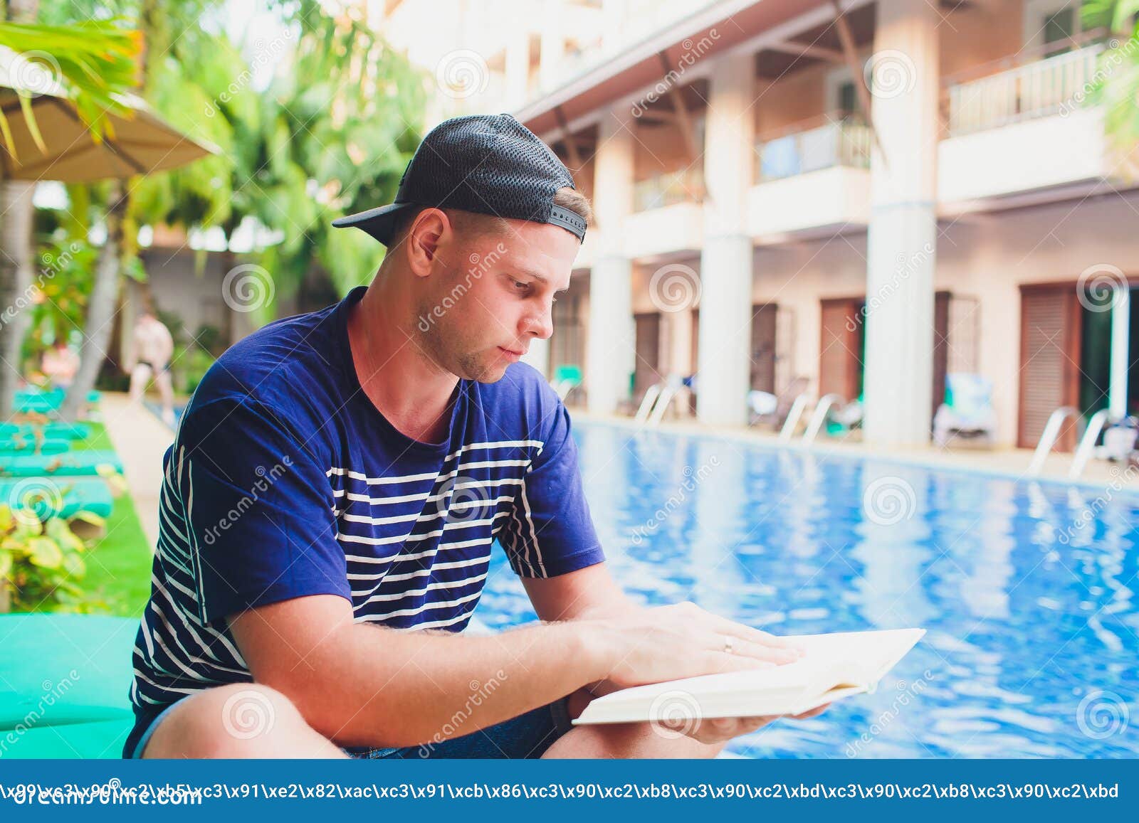 A Man Reading Book beside Swimming Pool in the Garden. Stock Photo ...