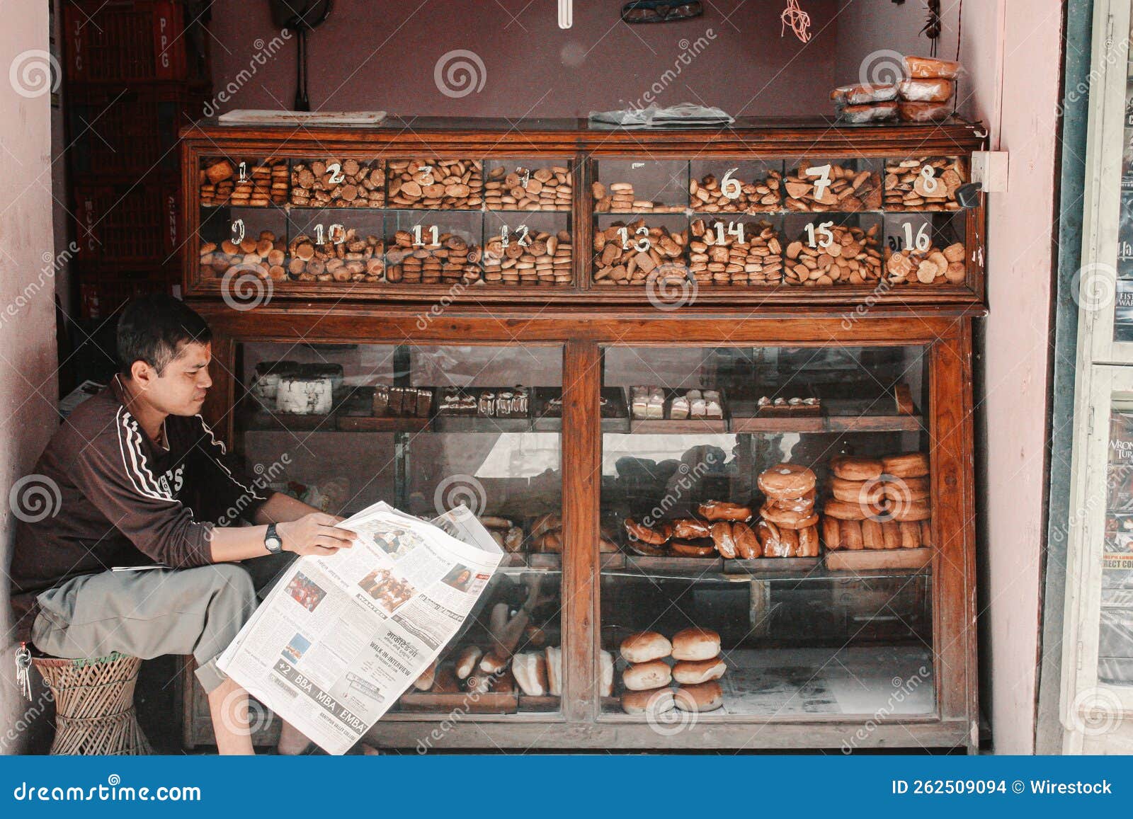 Man Reading the Newspaper while Sitting in Front of a Nepali Bakery ...