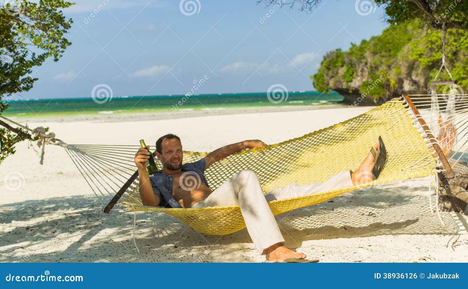 Man Relaxing in a Hammock on the Beach on Holidays. he is Drinking Beer ...