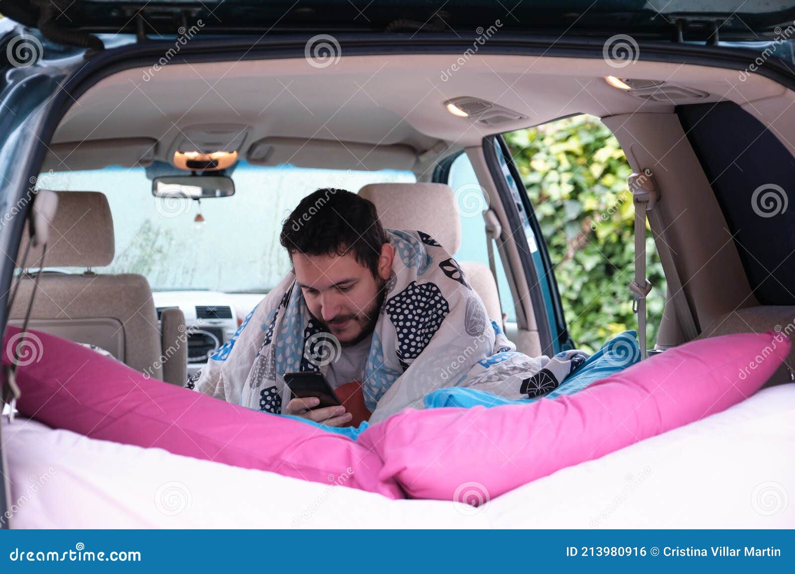 Man Relaxing and Using His Smartphone in a Bed Inside His Car Stock ...
