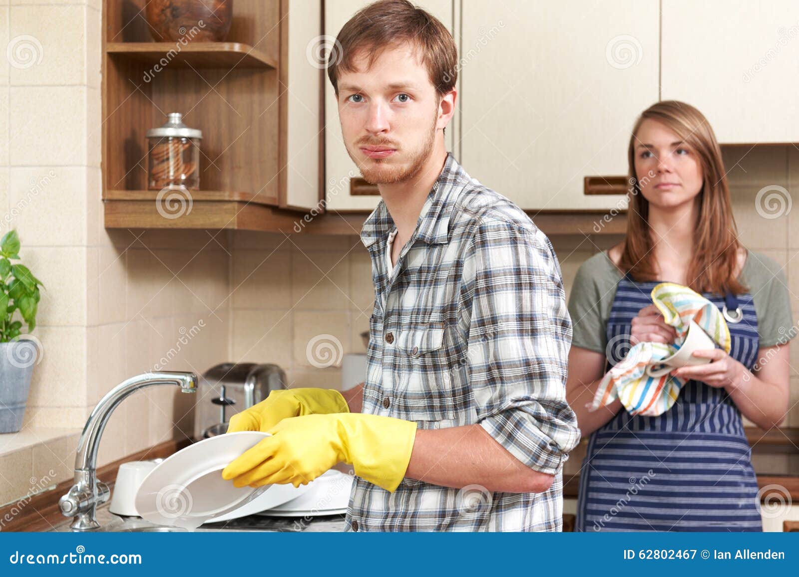 Man Reluctantly Washing Up in Kitchen with Partner Stock Image - Image ...