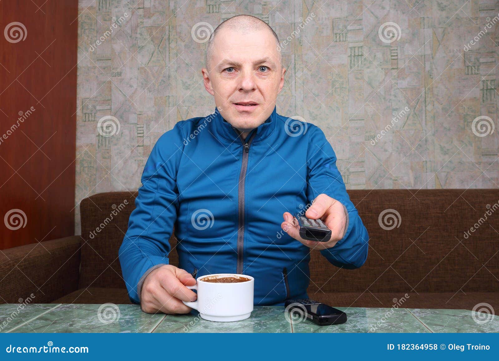 Man with the Remote for the TV in Hand, Drinking Coffee Stock Photo ...