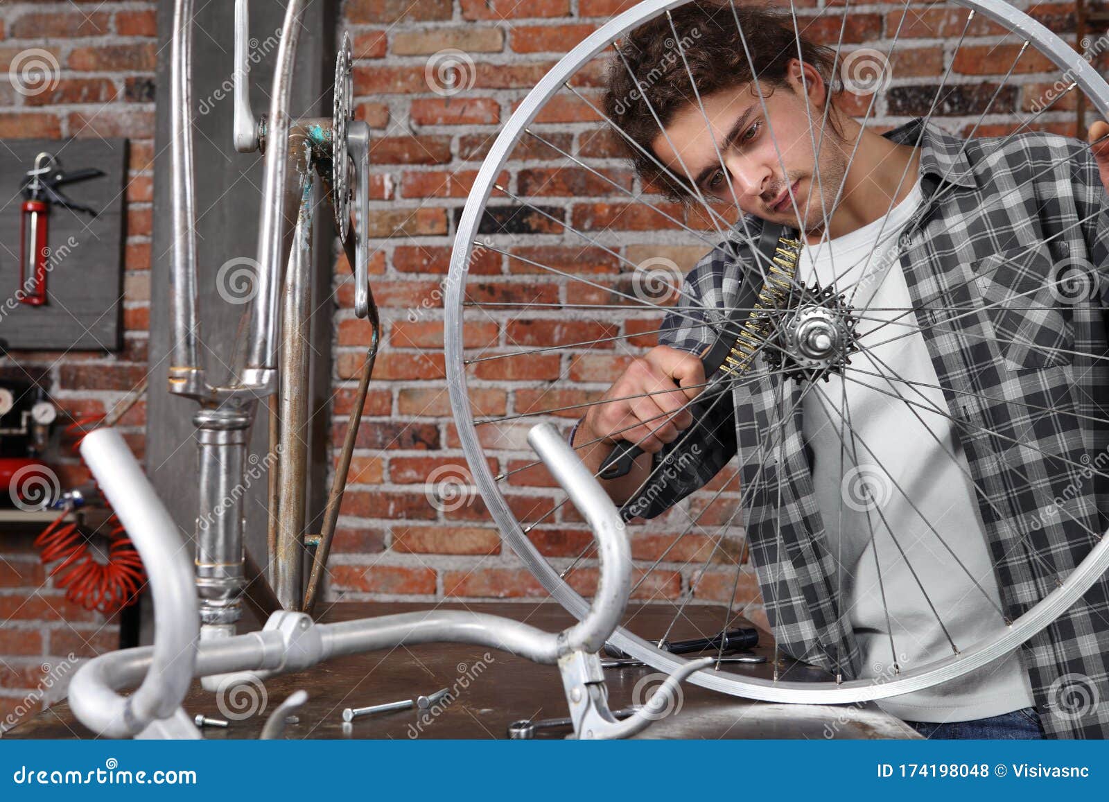 Man Repair the Bicycle in Garage Workshop on the Workbench with Tools ...
