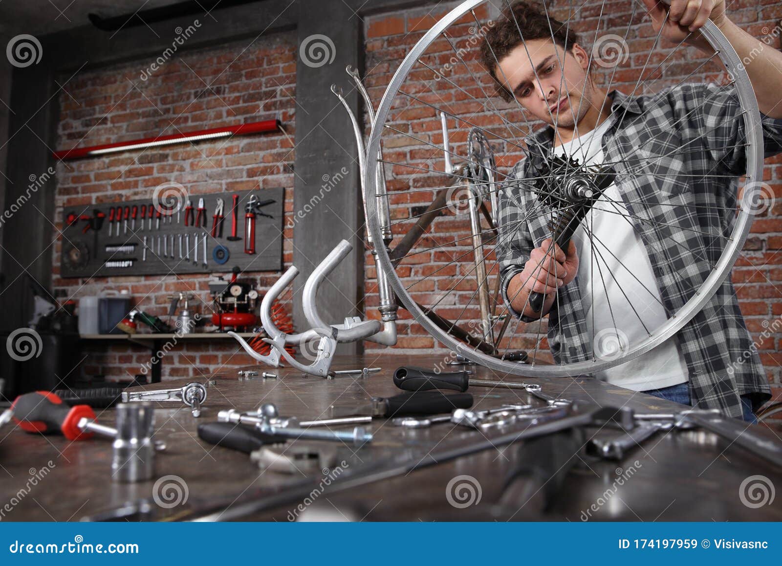 Man Repair the Bicycle in Garage Workshop on the Workbench with Tools ...